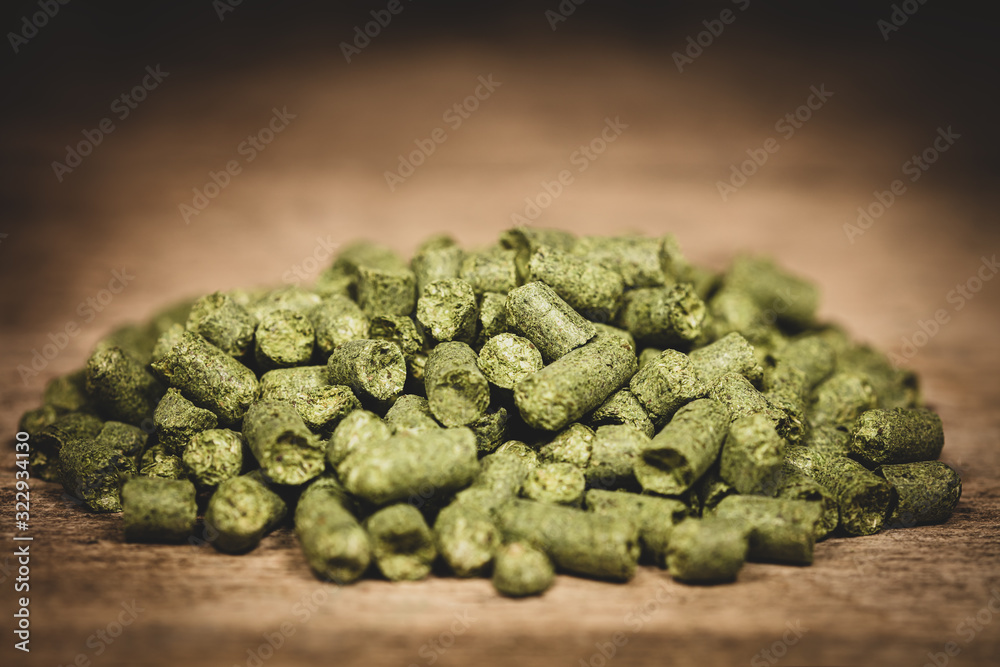 Dried green hop pellets on wooden ground, ingredient for a brewery or ...