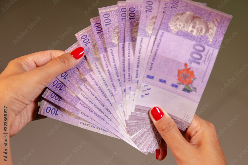 Female Hands with red nails counting 100 Ringgit banknotes. Ringgit the ...