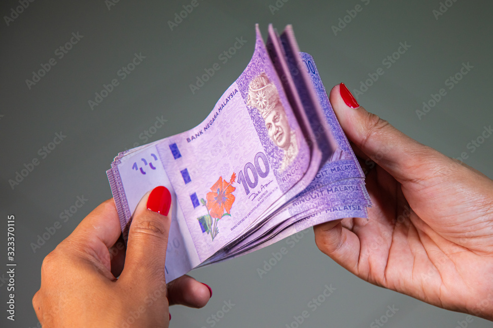 Female Hands with red nails counting 100 Ringgit banknotes. Ringgit the ...