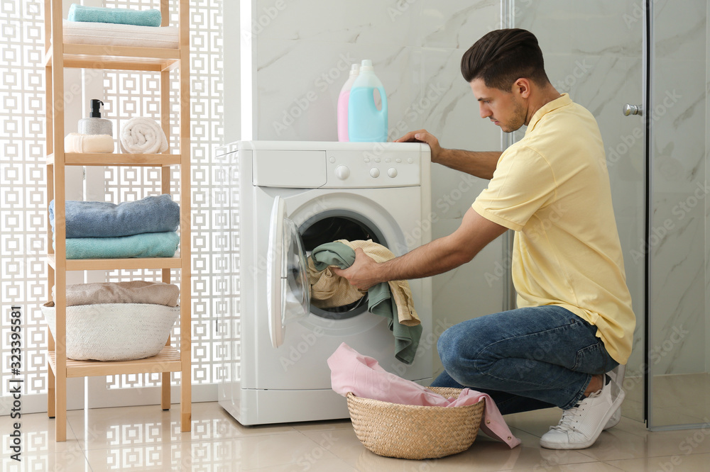 Man putting clothes into washing machine in bathroom. Laundry day Stock ...