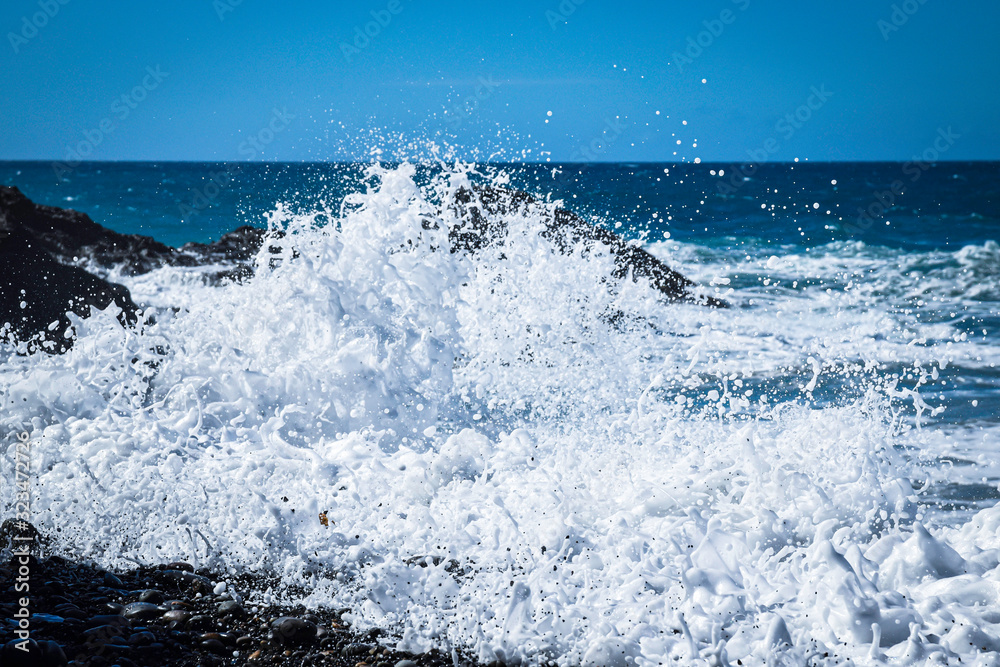 Large wave breaking on black rocks at Ajuy beach in Fuerteventura. Lots ...