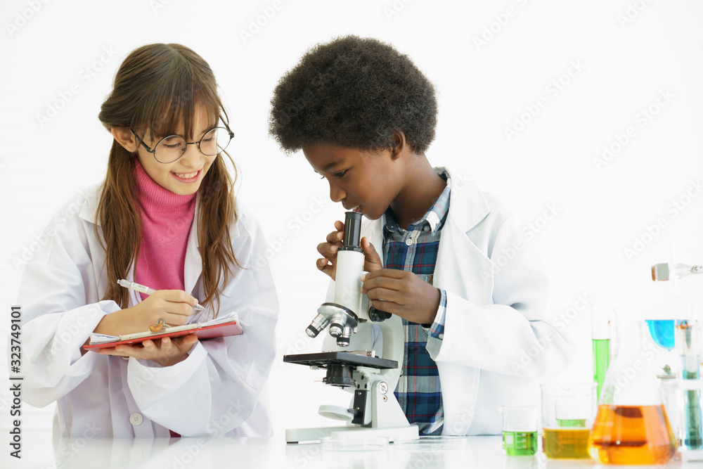 Children learning class using microscopes and take note in school ...