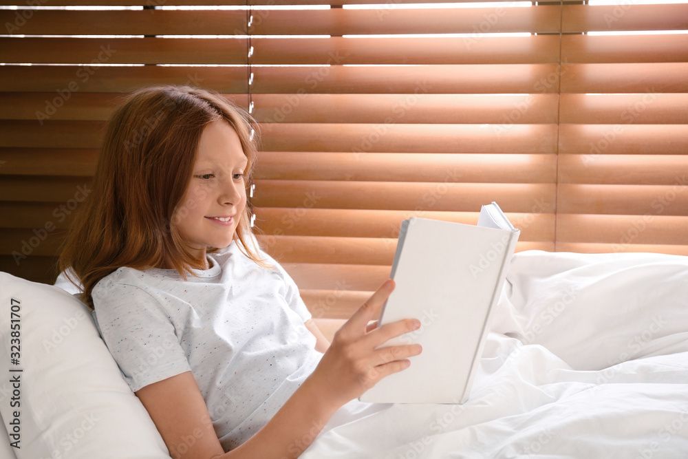 Cute preteen girl reading book in bed near window Stock Photo | Adobe Stock
