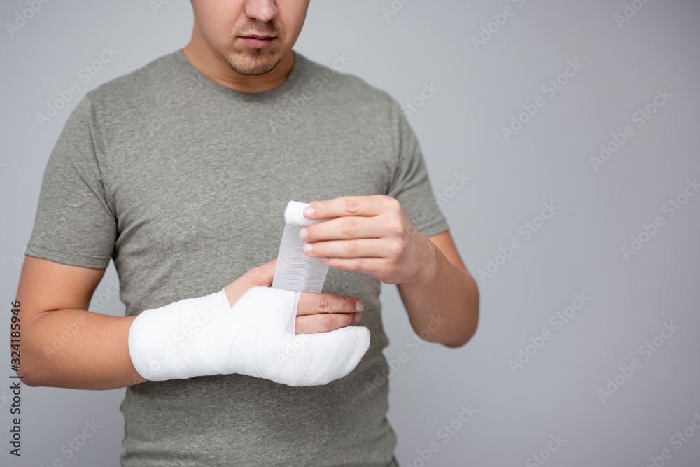 fracture and first aid concept - close up of young man bandaging his ...