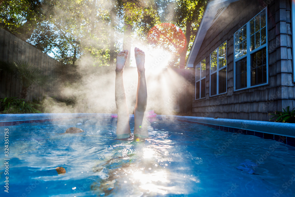 A teenage girl swimming in a pool, diving into warm water, steam rising ...