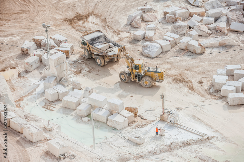 Mining industry: wheel bulldozer loading marble blocks in a dumper ...