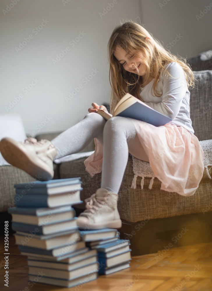 Little girl reading book. Girl with a pile of books at home. Having fun ...