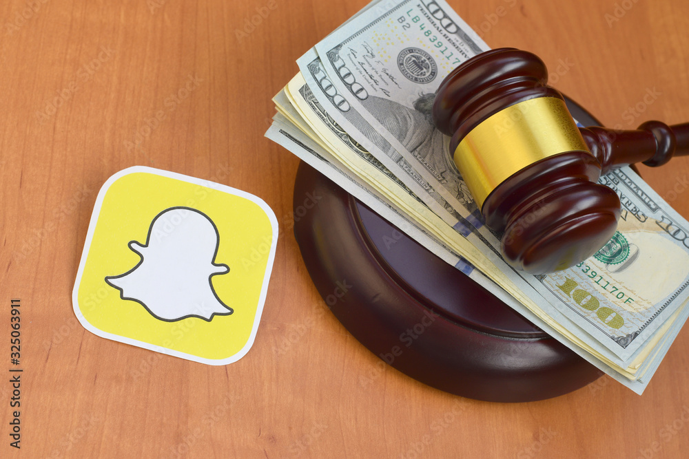 Snapchat paper logo lies with judge gavel and hundred dollar bills ...