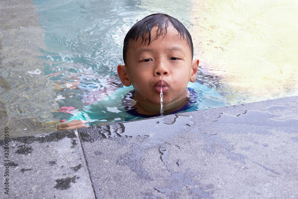 Boy play split water from mouth on poolside and play water in swimming ...