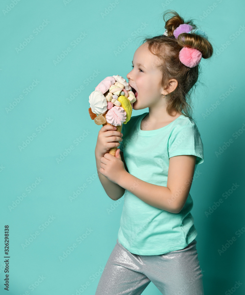 Portrait of happy kid girl eating biting big ice cream in waffles cone ...