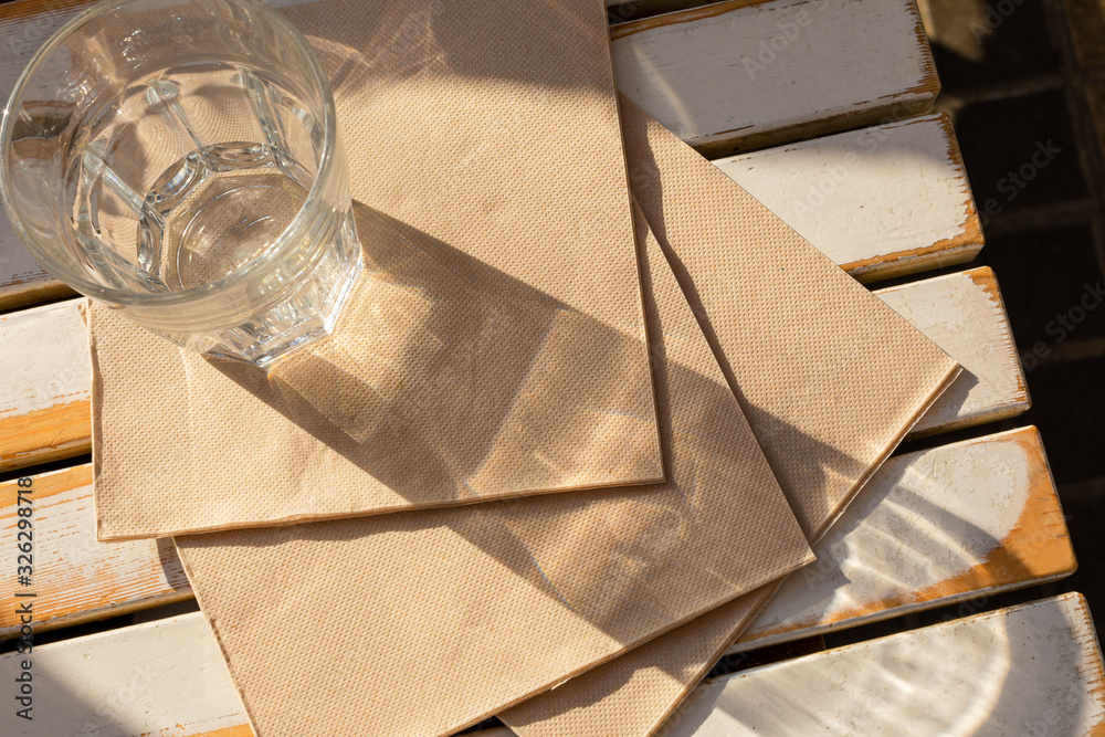 A recycled paper napkins and glass of water are on the cafe's light ...