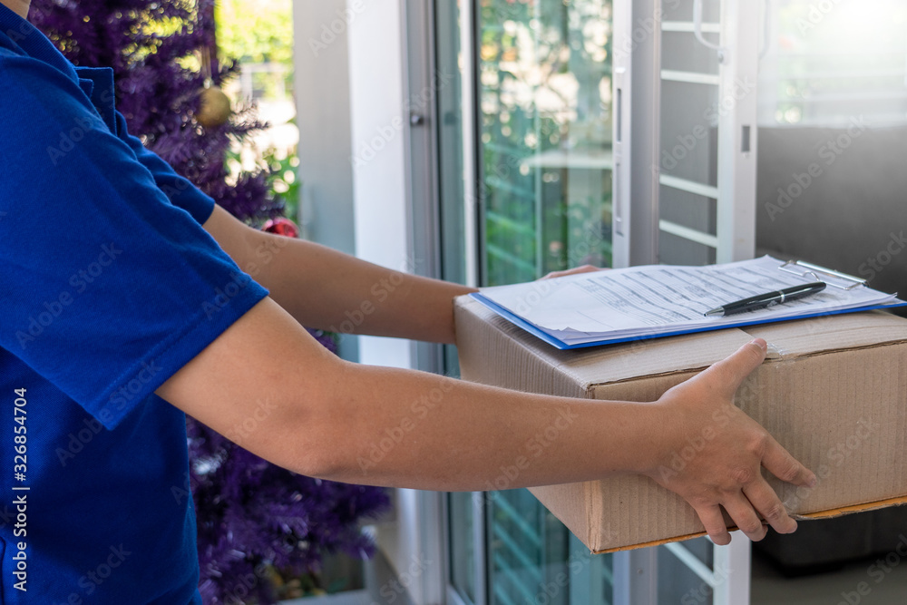Delivery man in blue uniform handing parcel box for client signing ...