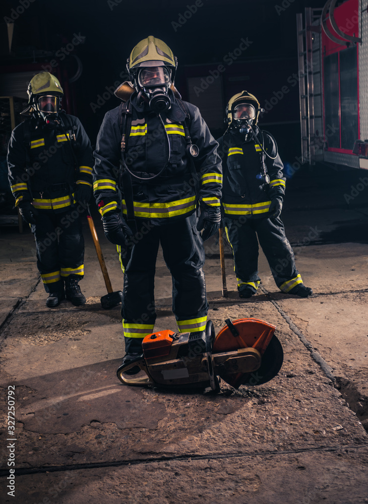 Group of three young fireman posing inside the fire department with ...