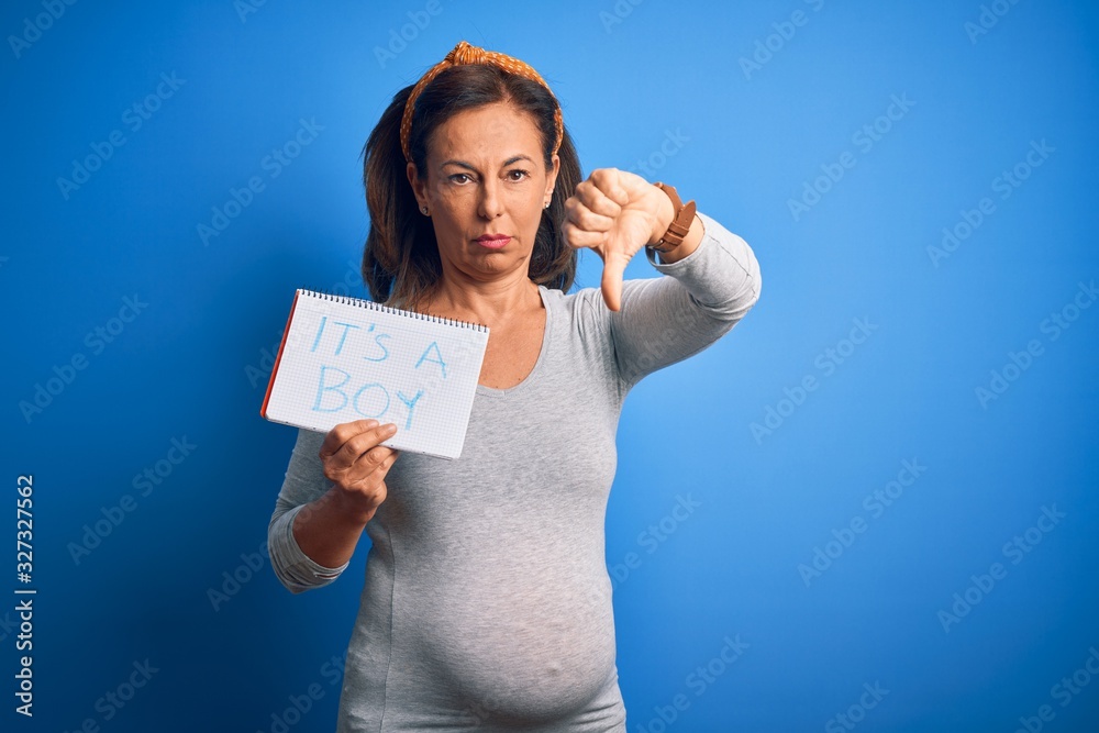 Middle age pregnant woman expecting baby boy over blue background with ...