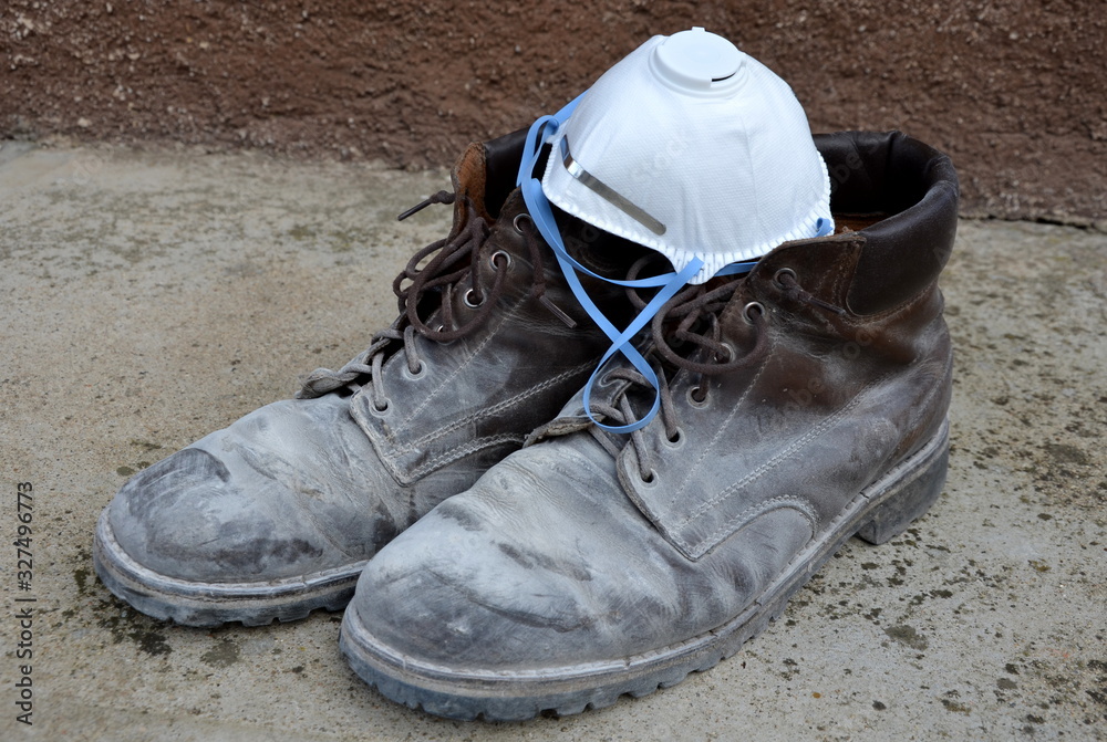 dusty work boots on a pile of sand with a respirator or mask to protect ...