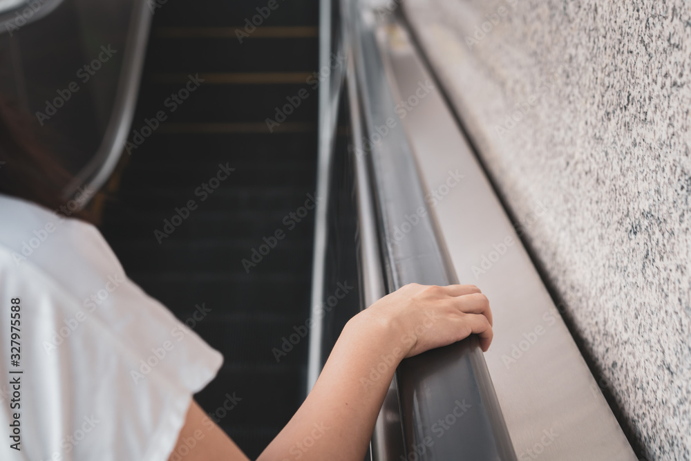 Woman grabbing the escalator hand rail while standing on the escalator ...