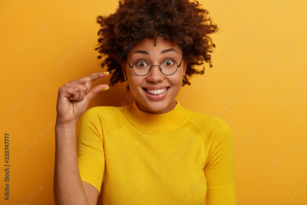 Little bit. Pretty smiling woman measures tiny invisble object, smiles ...