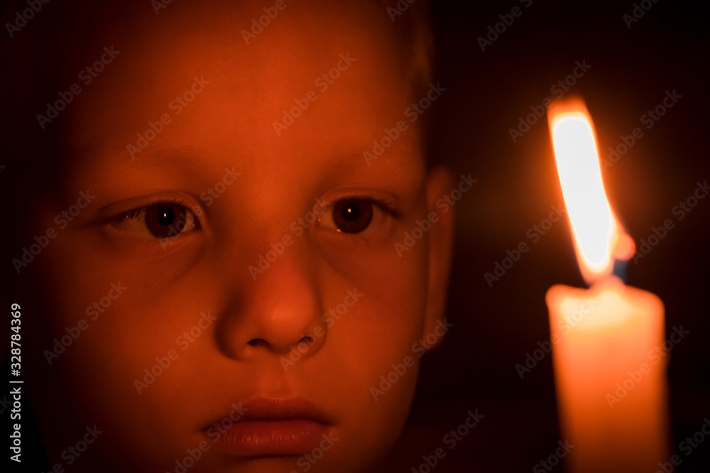Sad child looks at burning candle in the dark. Concept of loss, tragedy ...