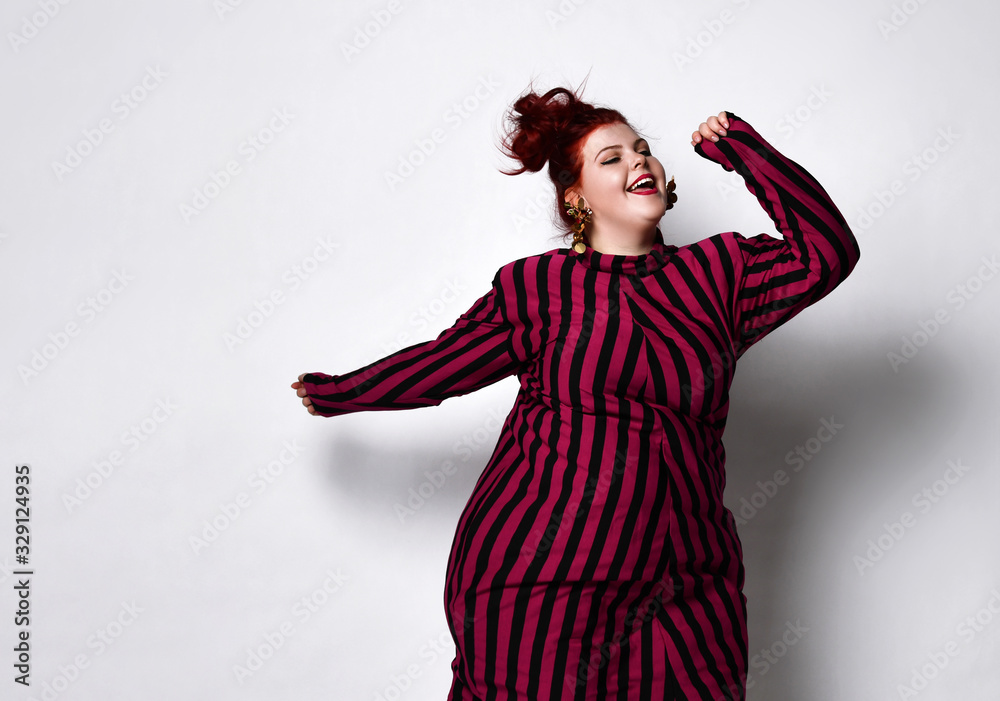 Fatty ginger girl in striped dress, earrings. She is smiling, dancing ...