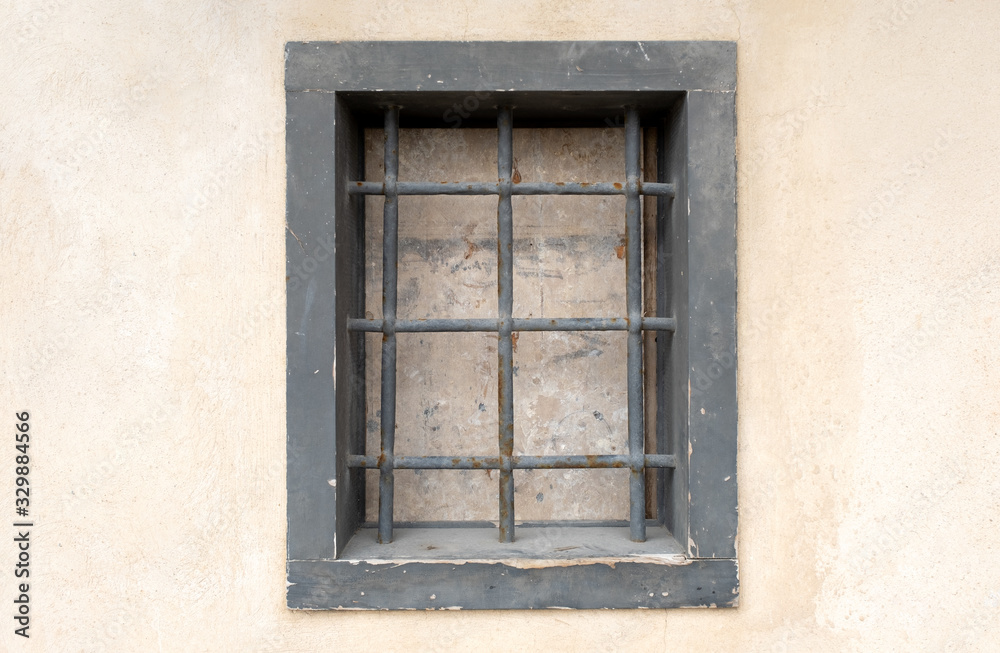 window with bars in the old city. there is one window on the wall which ...