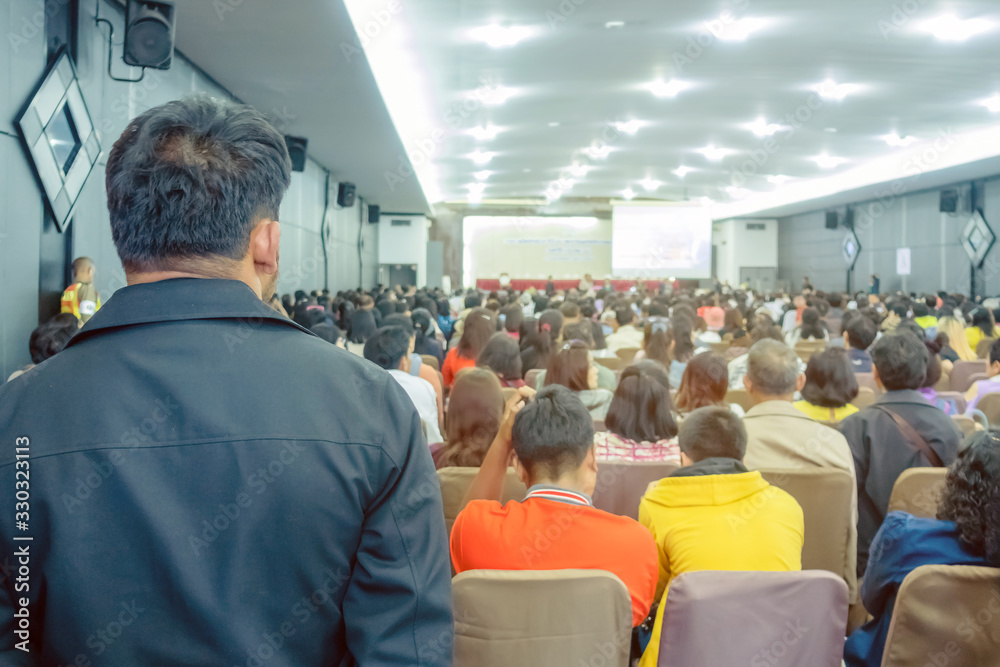 Backside view of spectators standing in a gathering in the back of ...