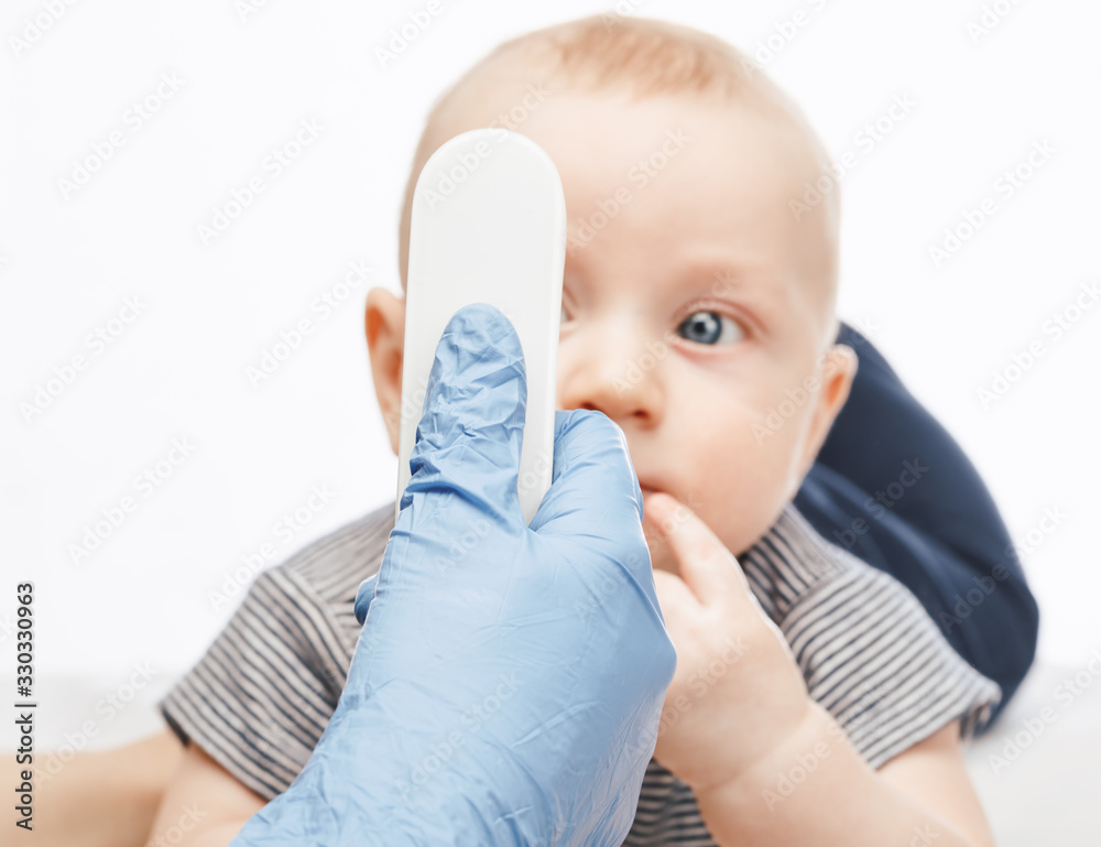 Pediatrician using infrared thermometer checking body temperature of ...
