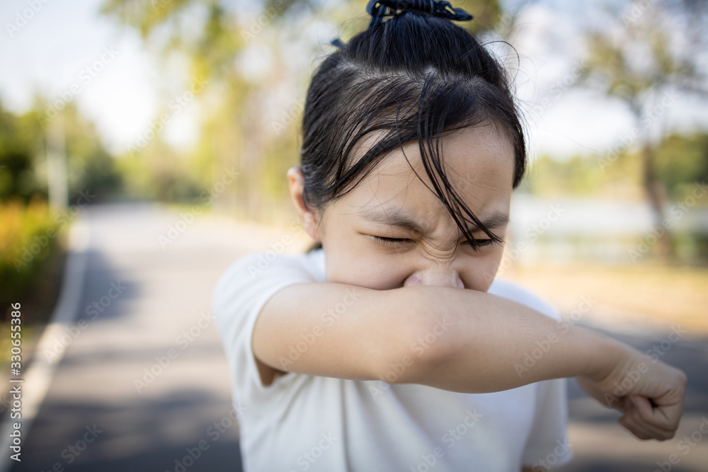 Foto Asian child girl sneezing,coughing into her arm or elbow to ...