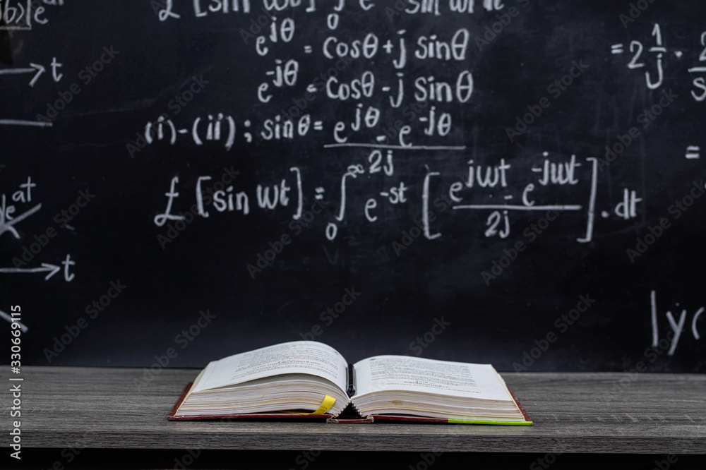 Open book on the table in classroom with blackboard background, back to ...