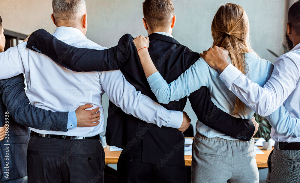 Coworkers Standing Back To Camera Embracing During Meeting In Office ...