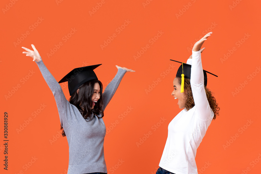 Happy excited young female students wearing graduate caps smiling with ...