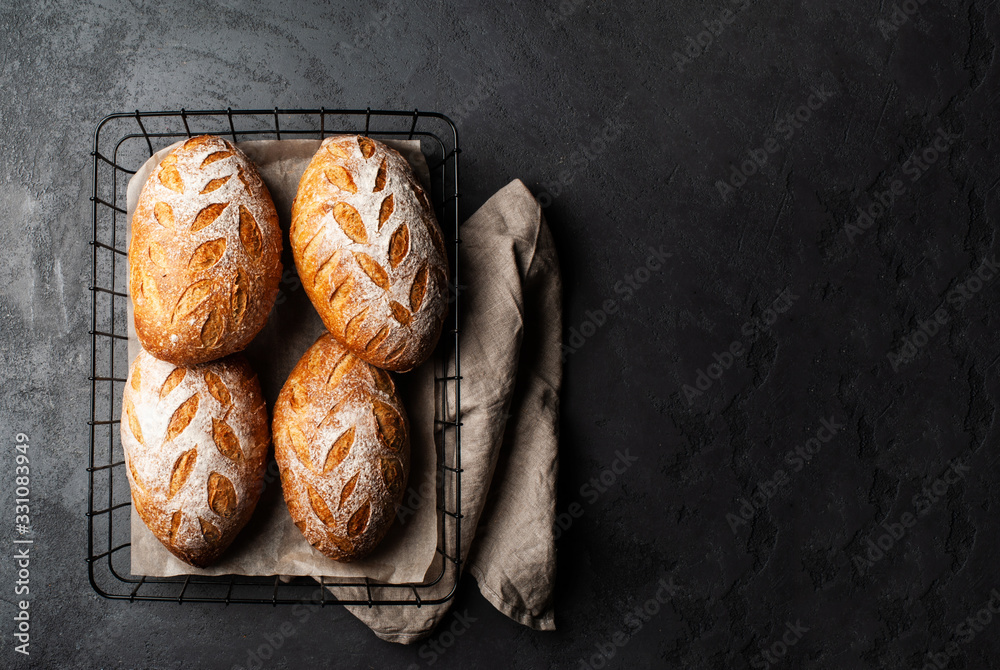 Freshly baked traditional bread in basket on concrete table. Dark moody ...