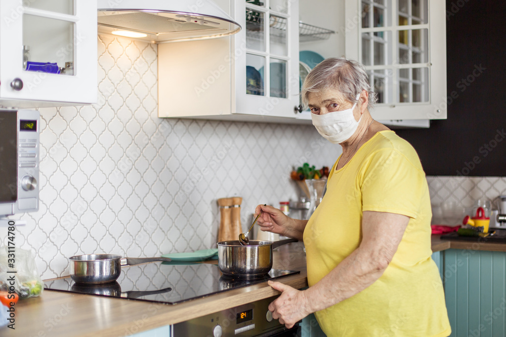 Foto old woman in mask quarantine europe cooks in the kitchen in the ...
