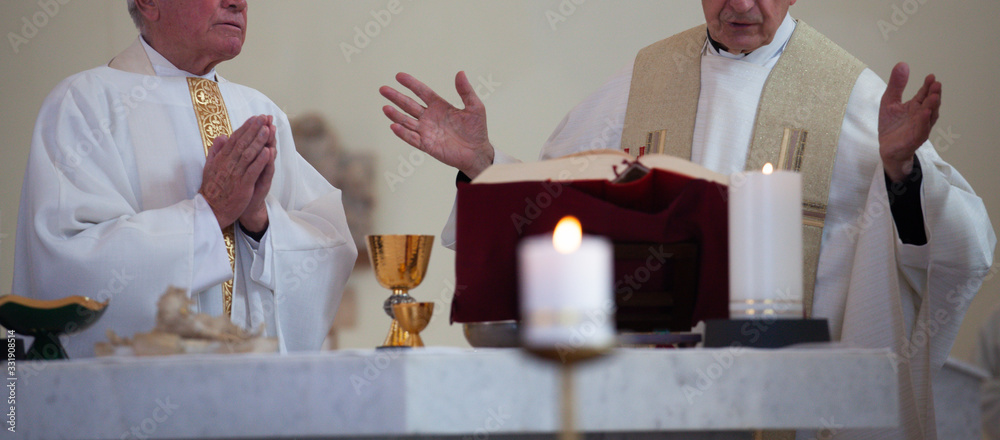Two priests dressed in liturgical vestments celebrate the Holy Mass in ...