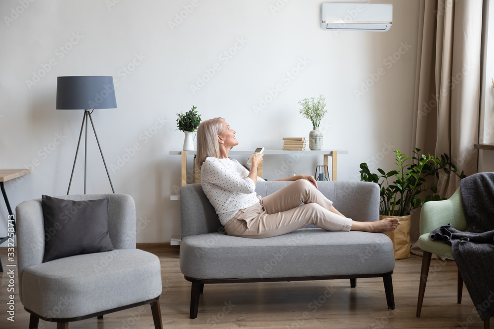 Full length happy older lady relaxing on cozy sofa in modern living ...