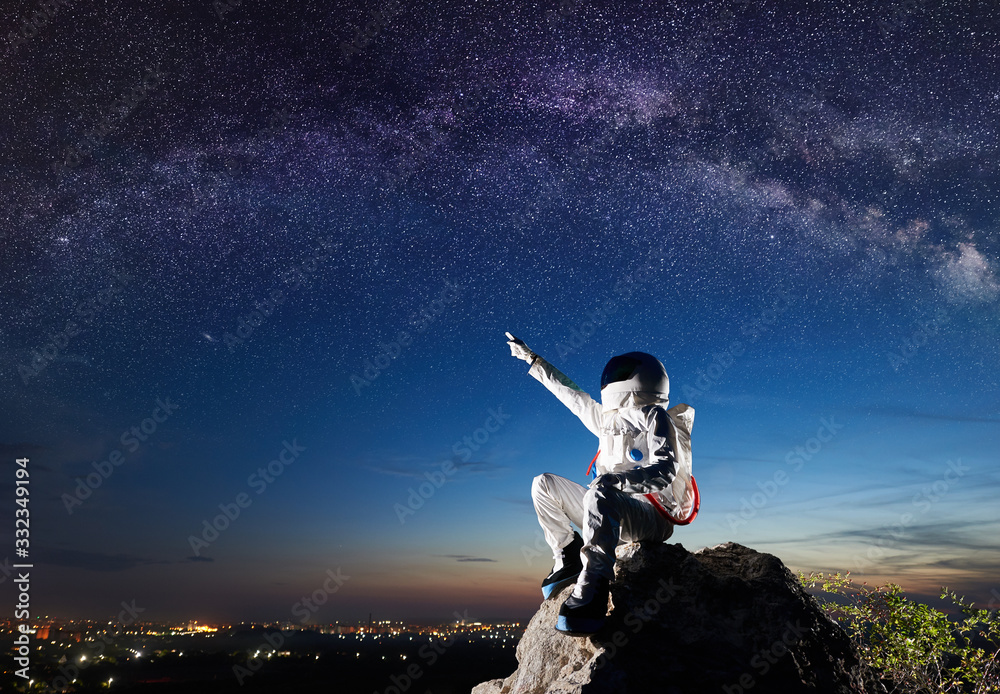 Side view of spaceman pointing at beautiful sky with stars while ...