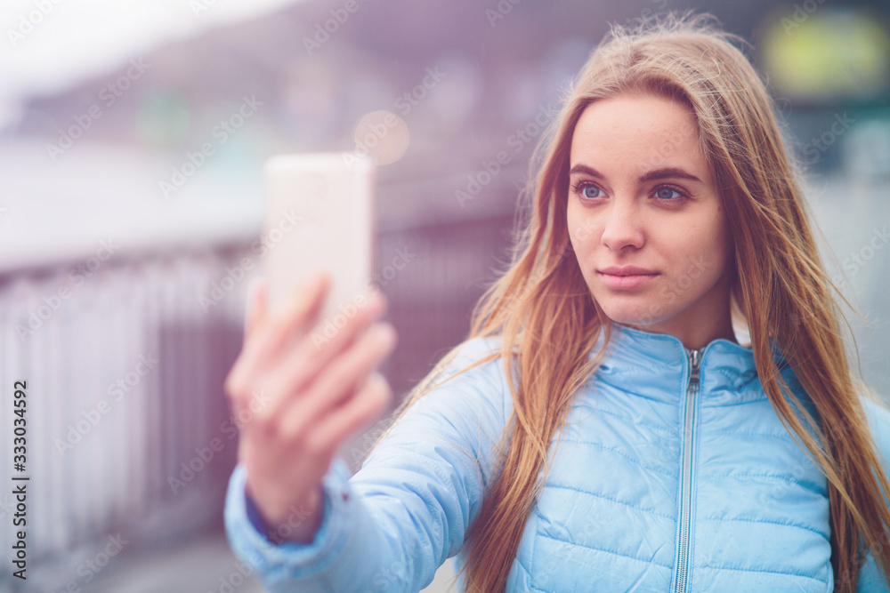 Pretty woman taking a selfie. Beautiful girl walking on the streets and ...