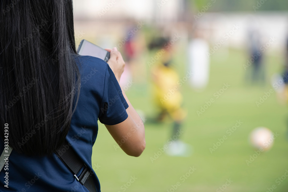 Mother standing, watching and taking pictures of her daughter playing ...
