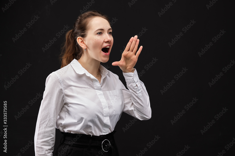 Girl in a white shirt hand shows a scream on a black background. Stock ...