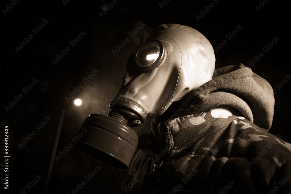 Gas mask with clouds of smoke on a dark background. Sign of radioactive ...