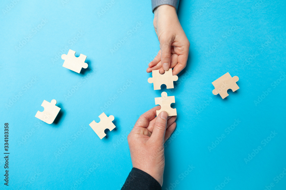Two hands connect puzzles on a blue background. Cooperation and ...
