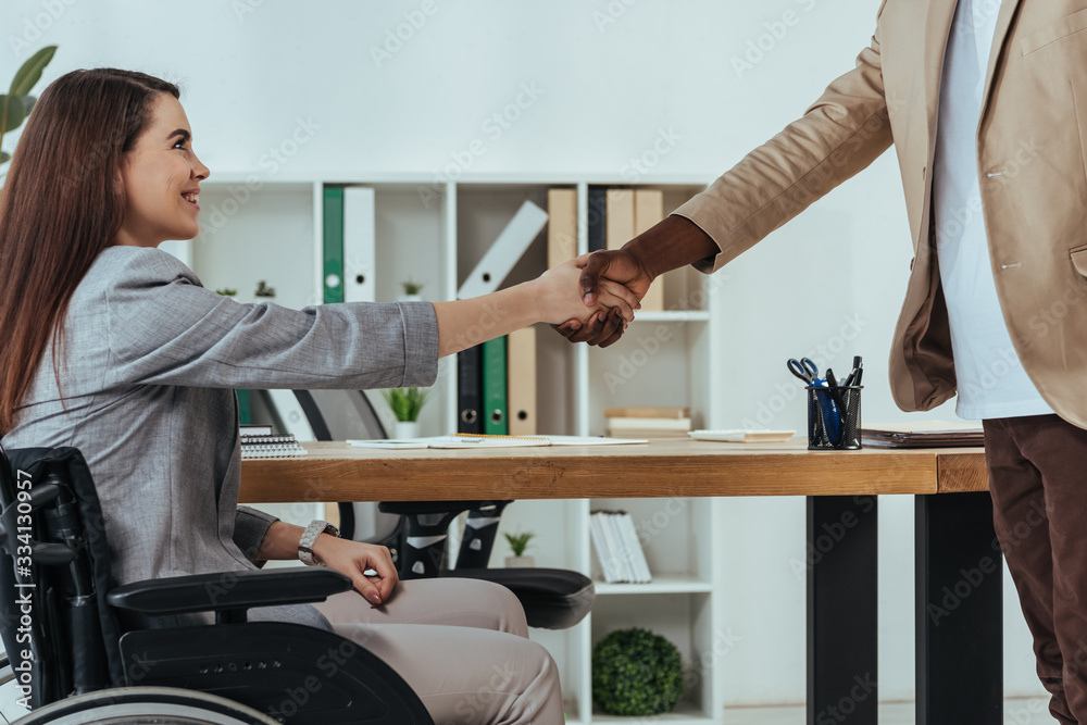 Disabled employee and african american recruiter shaking hands at job ...