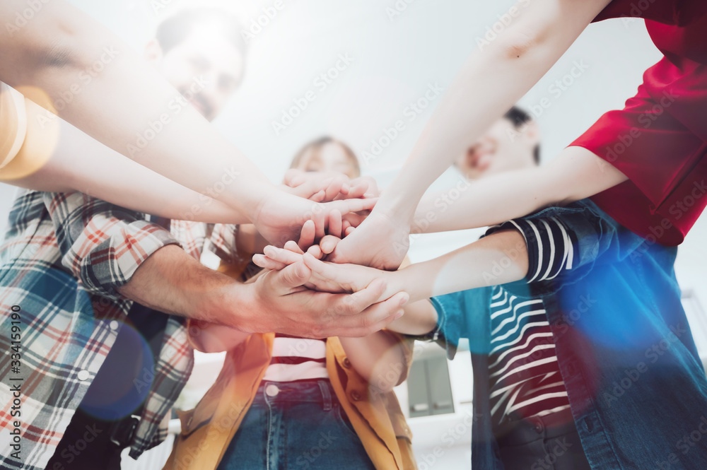 Co-working startup business team and teamwork concept. Young team putting hands up in creative ...