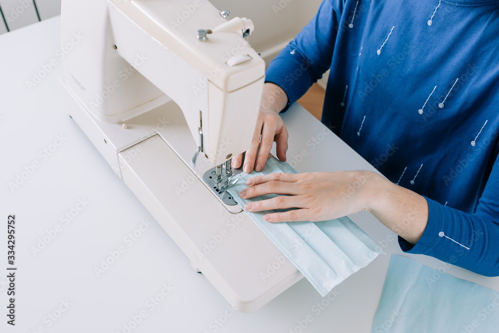 Woman hands using the sewing machine to sew the face home made diy ...