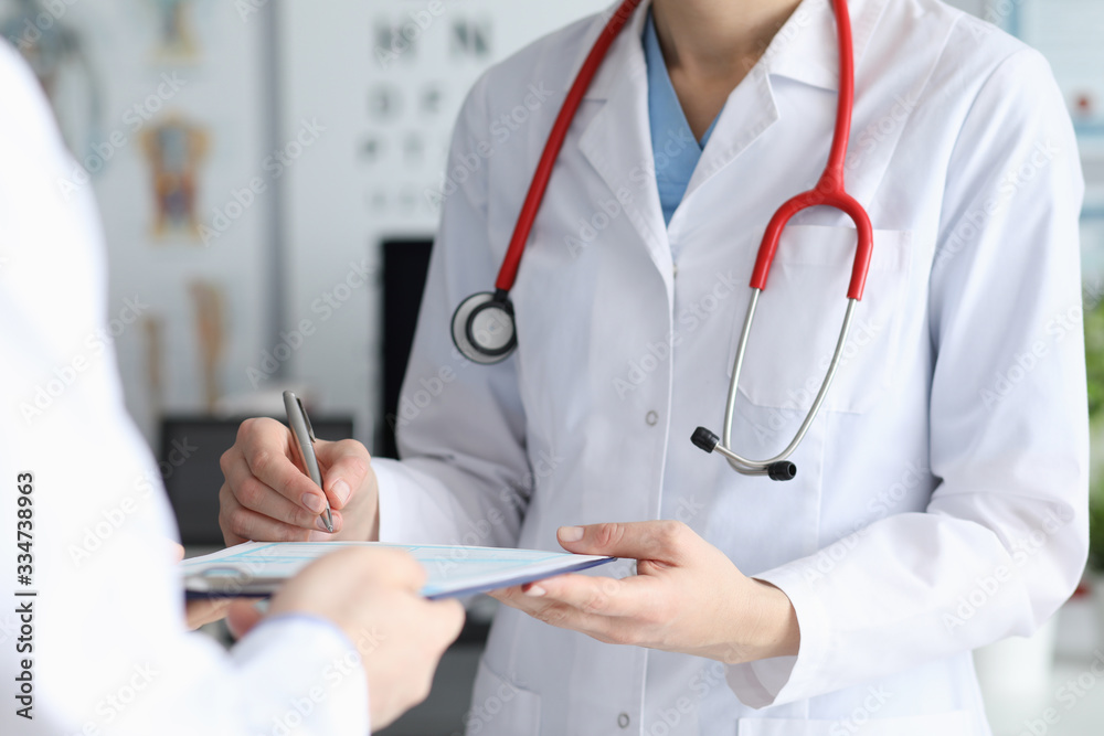 Female doctor signs patient card with diagnosis. Help qualified doctors ...
