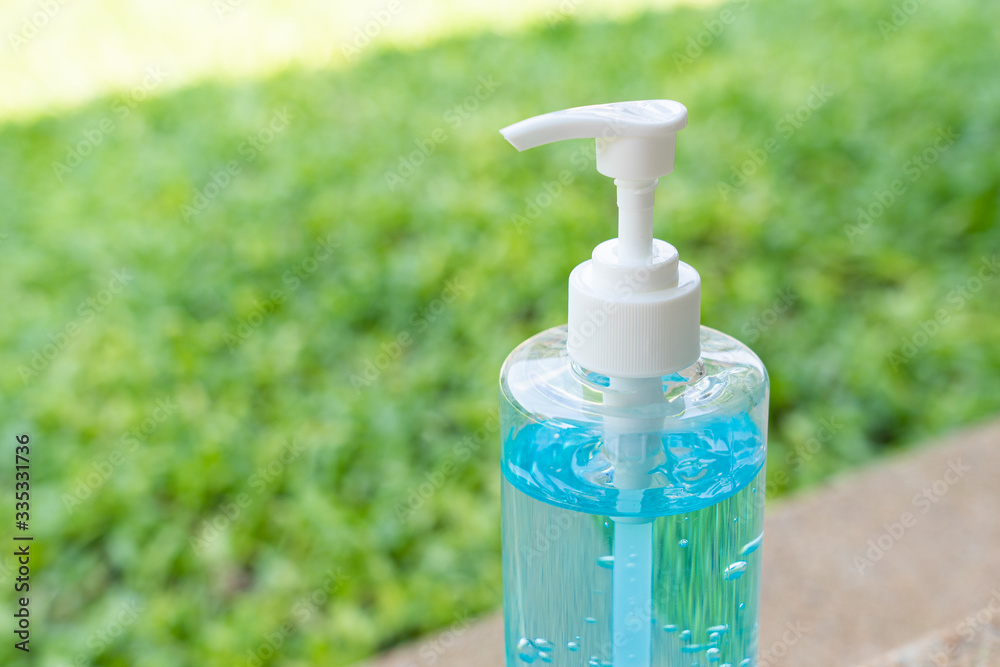 Blue hand sanitizer gel in clear pump bottle with grass background ...