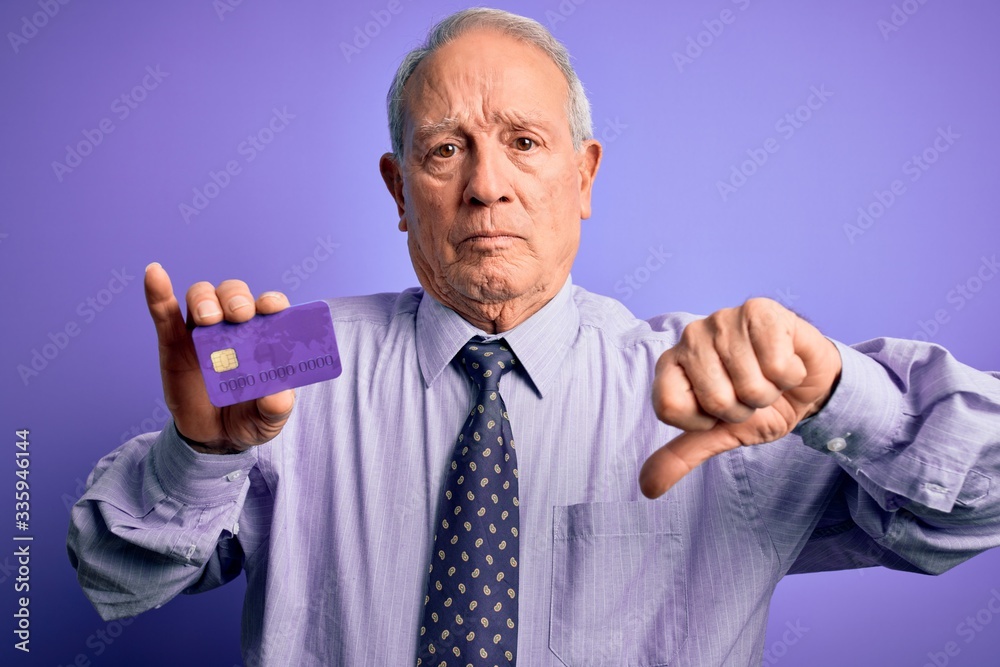 Senior grey haired business man holding credit card over purple ...