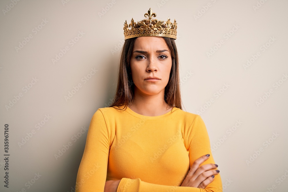 Young beautiful brunette woman wearing golden queen crown over white ...