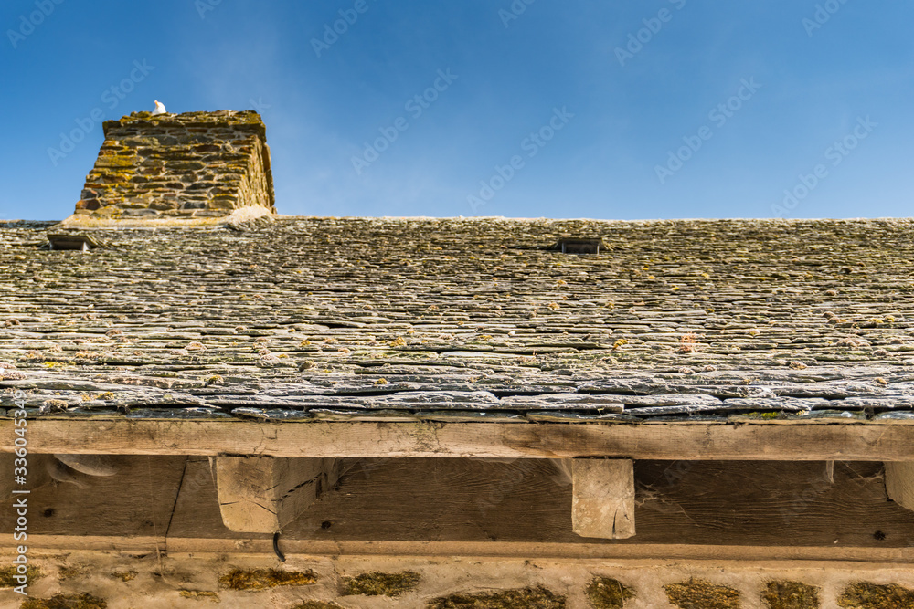 Old slate roof with wooden beams with cobwebs. a chimney on top with a ...
