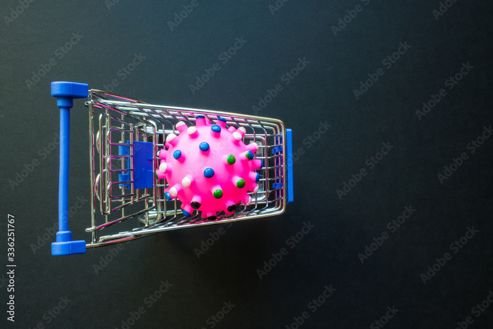 Pink coronavirus molecule in a metal grocery basket close-up on a black ...