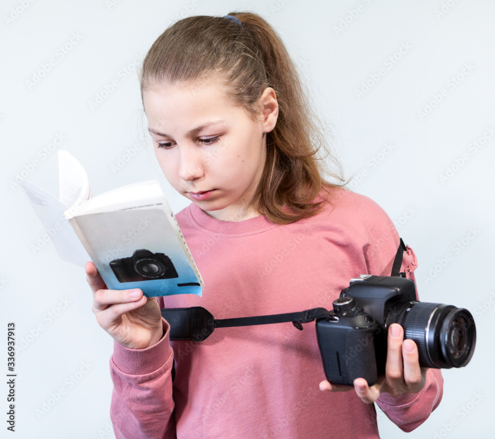 Teenage Caucasian girl reading user manual of DSLR camera, learning ...
